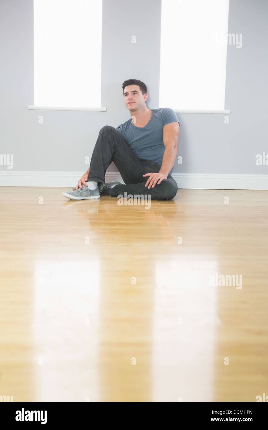 Thoughtful handsome man leaning against wall sitting on the floor Stock ...