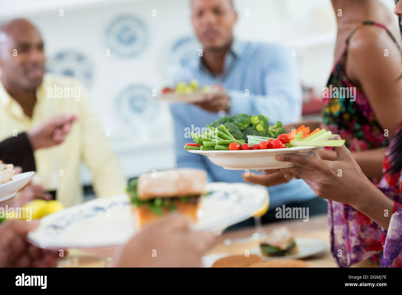 An informal office event. People handing plates of food across a buffet ...