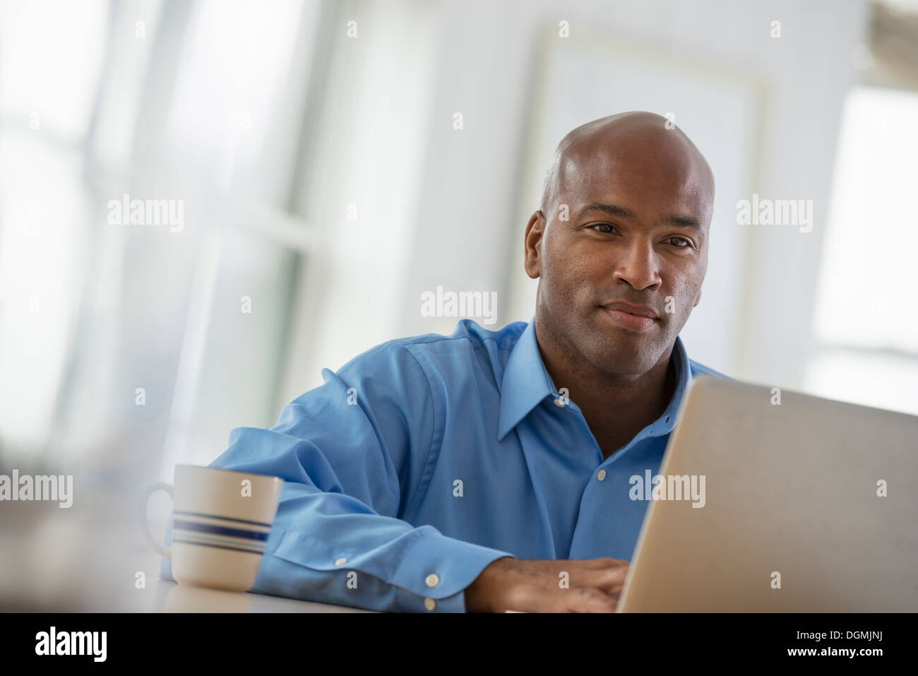 Office. A man sitting using a laptop Stock Photo - Alamy