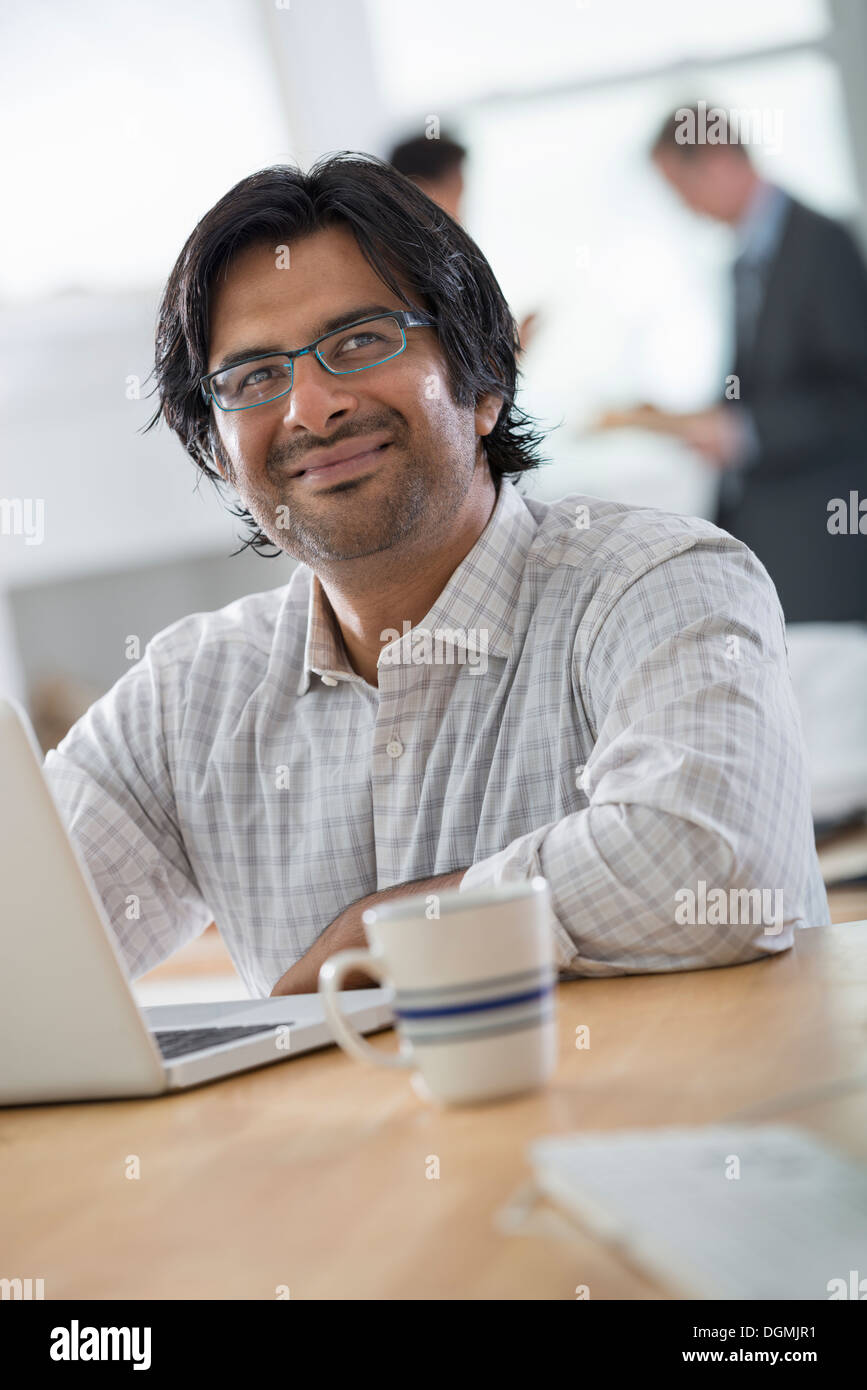A young man in an office using a laptop computer Stock Photo - Alamy