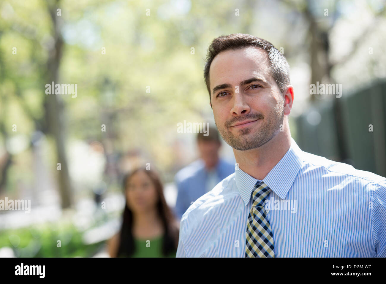 A small group of people, a businesswoman and two businessmen outdoors ...