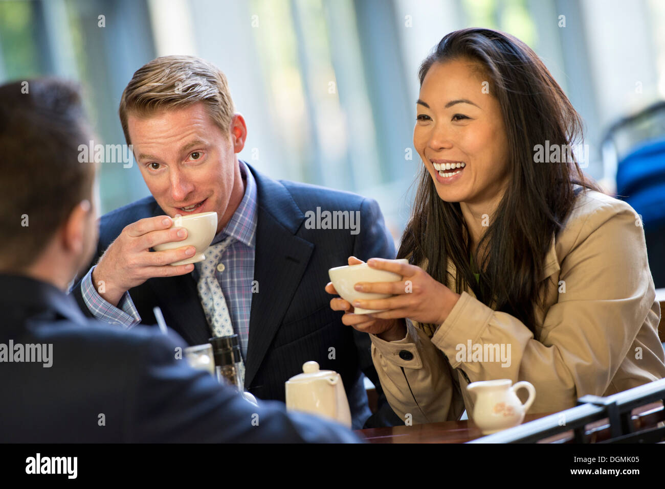 A businesswoman and two businessmen sitting in a coffee shop having a ...