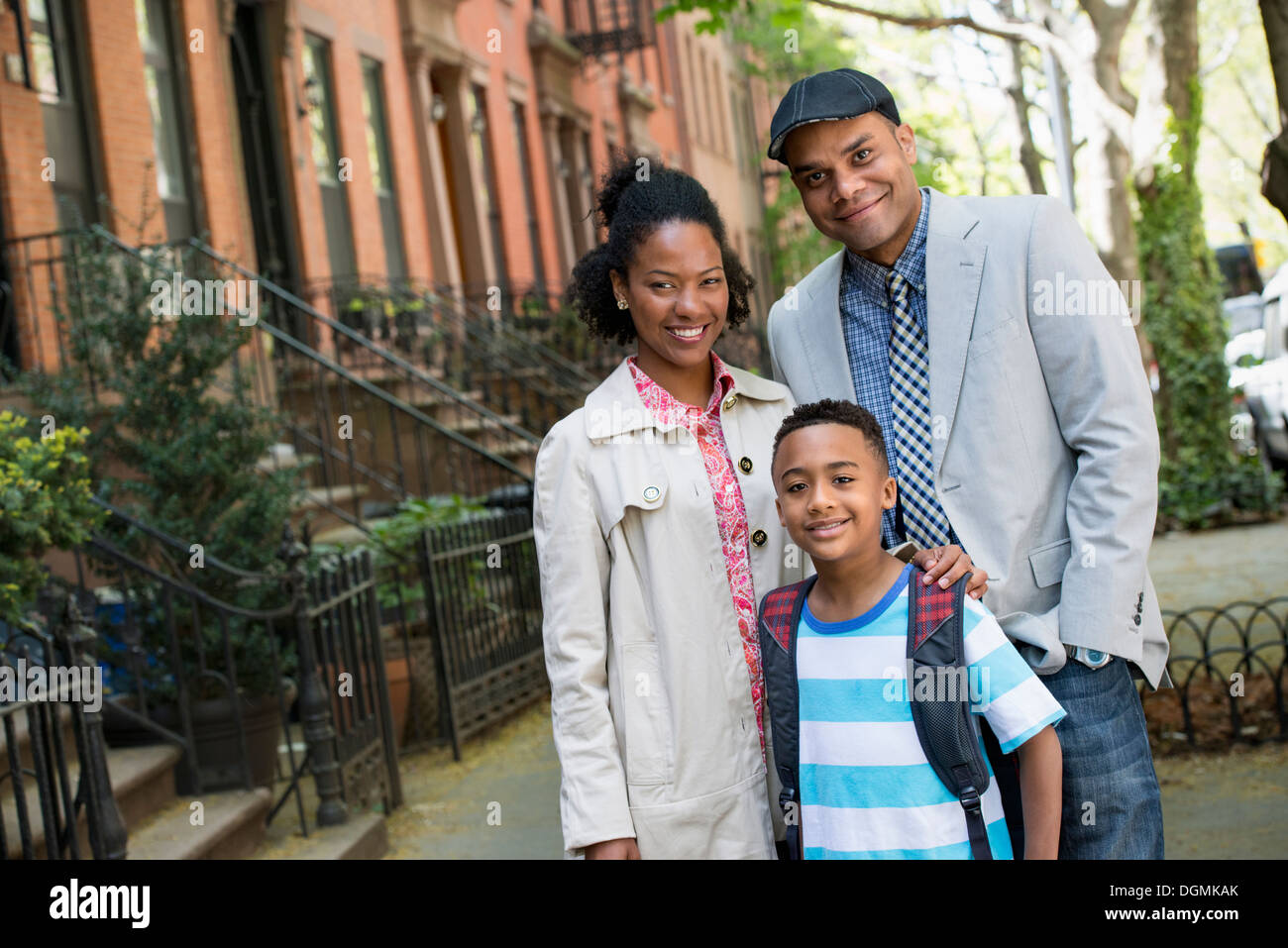 A family outdoors in the city. Two parents and a young boy walking ...