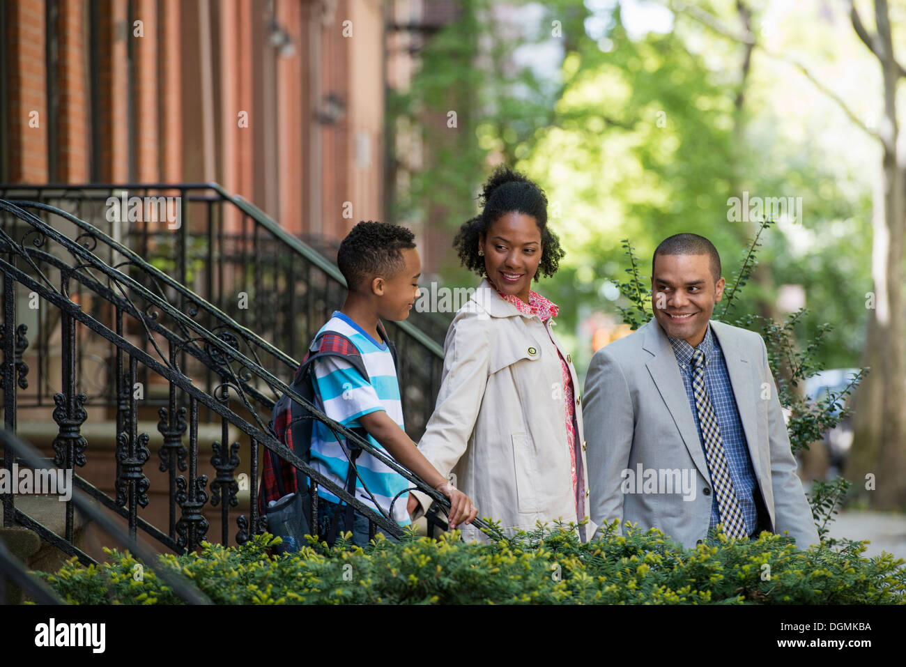 A family outdoors in the city. Two parents and a young boy walking ...