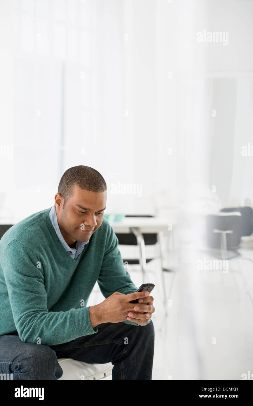 Business. A man seated, checking his smart phone for messages and ...