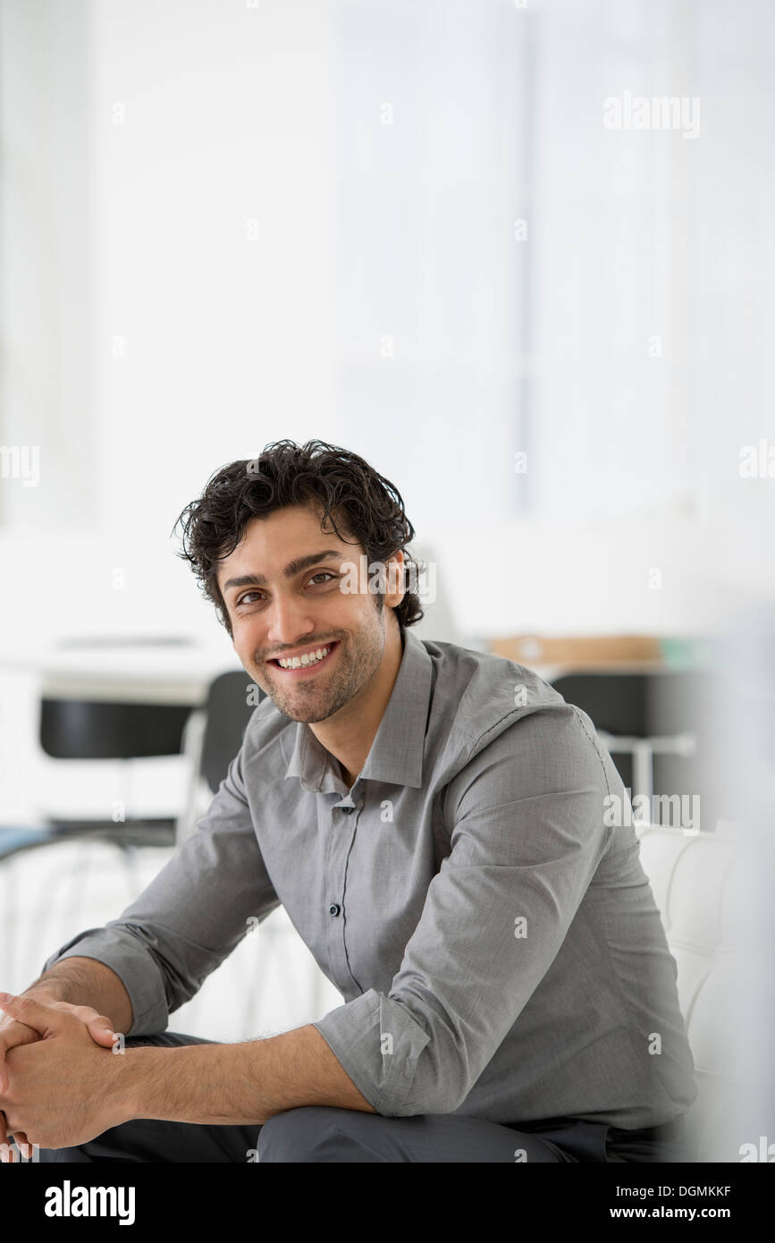 Business. A man seated with his hands clasped in a relaxed pose ...