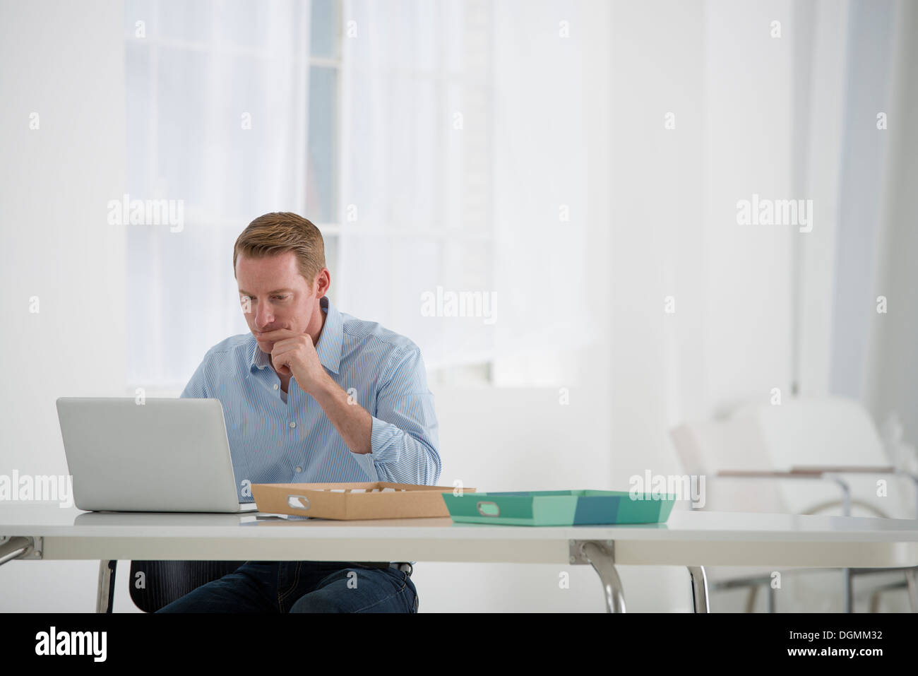 Business. A man sitting at a desk using a laptop Stock Photo - Alamy