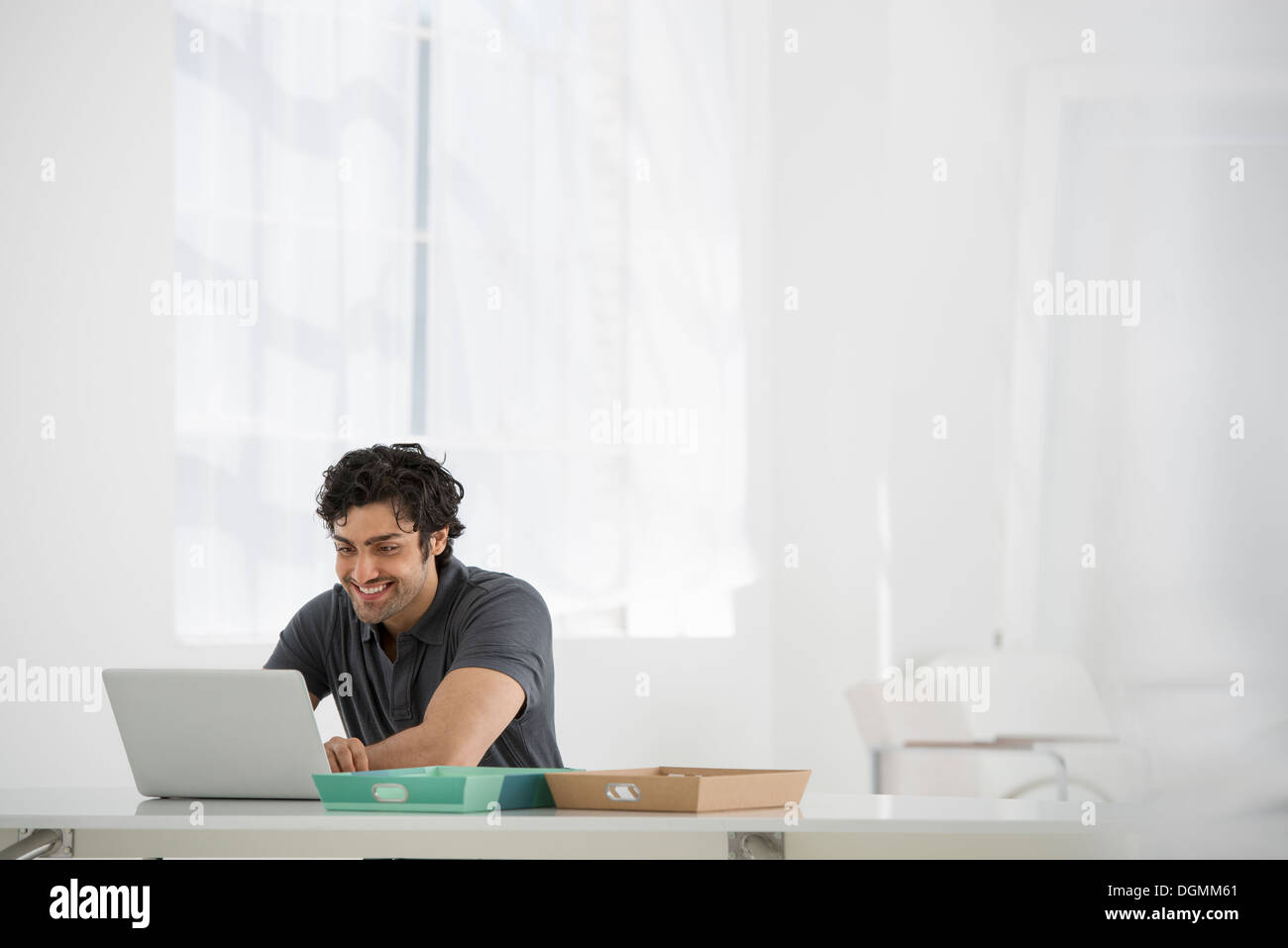 Business. A man sitting at a desk using a laptop Stock Photo - Alamy