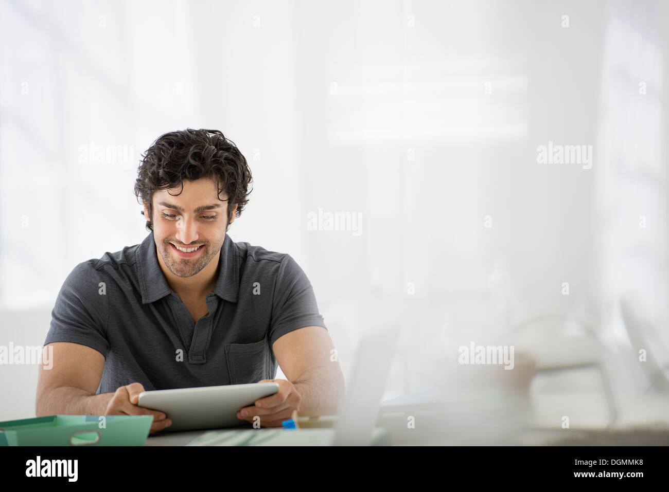 Business. A light airy office environment. A man sitting holding a ...
