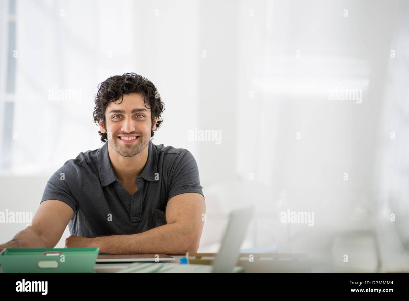Business. A man sitting in a relaxed pose behind a desk Stock Photo - Alamy