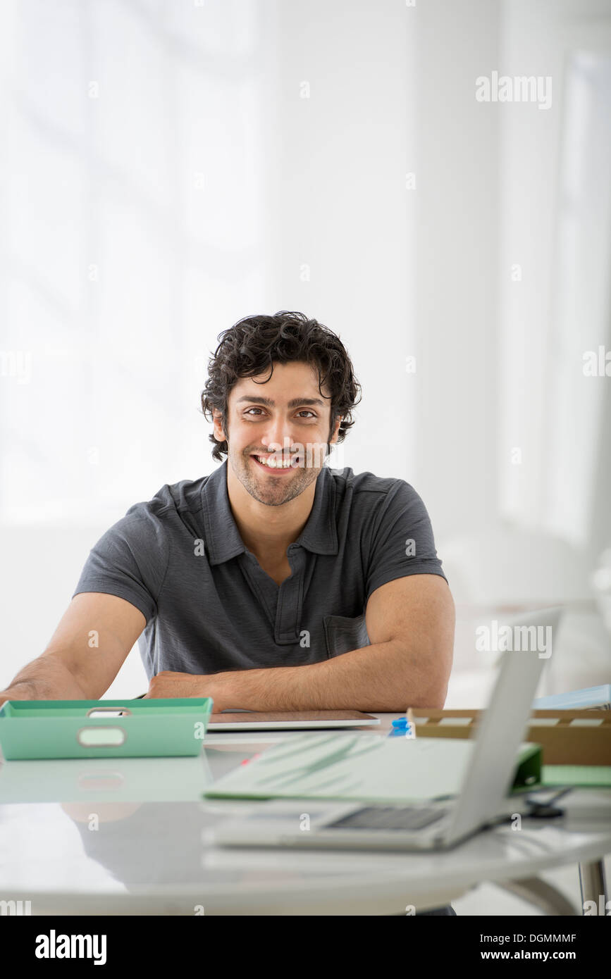 Business. A man sitting in a relaxed pose behind a desk Stock Photo - Alamy