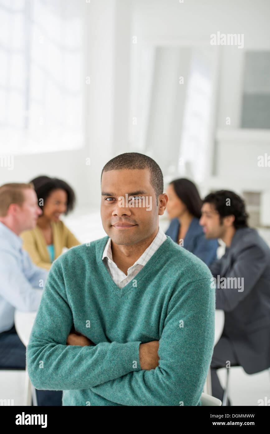 Business meeting. A group sitting down around a table. A man smiling ...