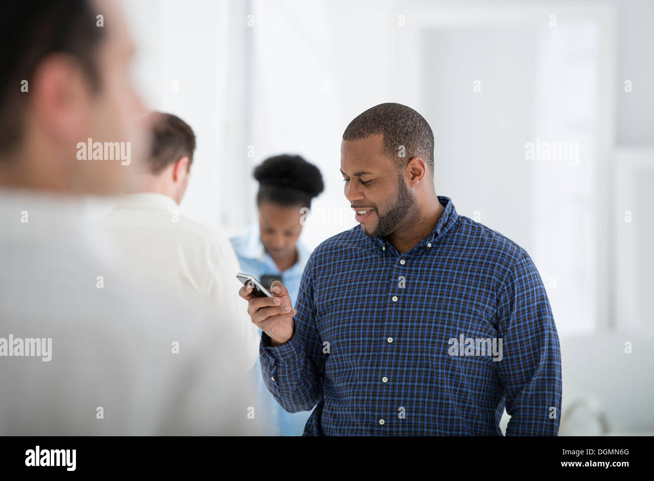 Office interior. A group of people, one man using a smart phone Stock ...