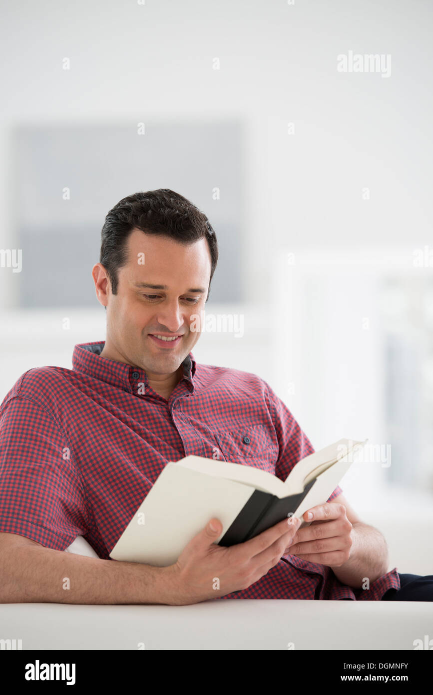 A bright white room interior. A man sitting reading a book Stock Photo ...