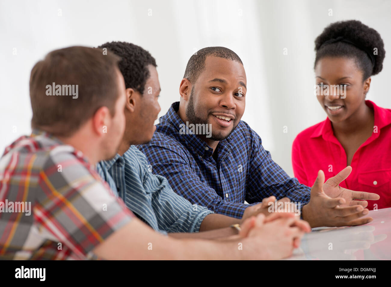 Office. A group of four people, two men and two women seated talking ...