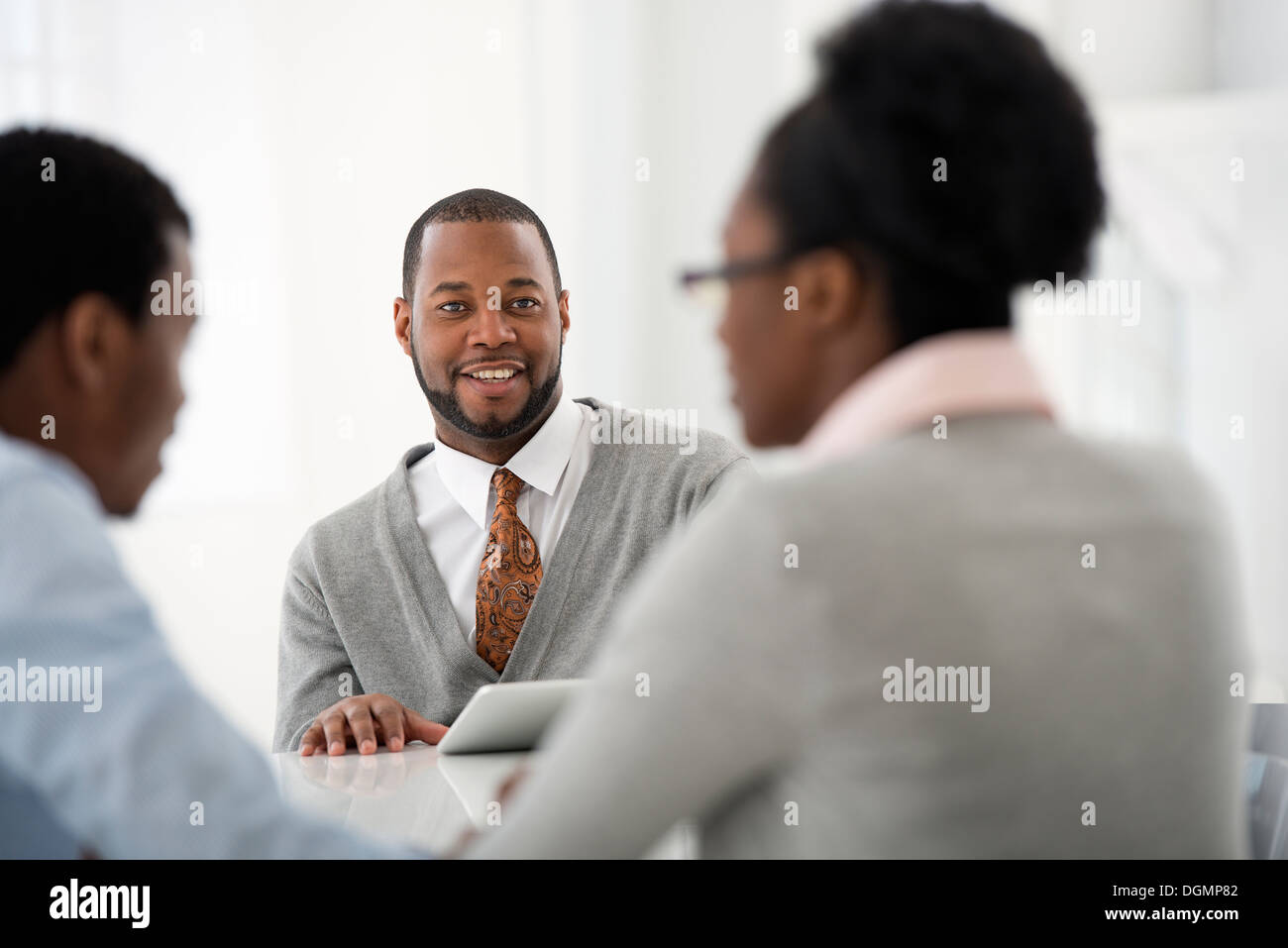 Office interior. Three people sitting around a table at a business ...