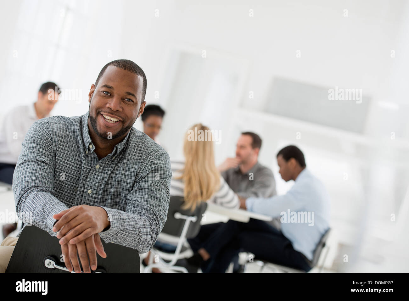 Office interior. A man seated separately from a group of people seated ...