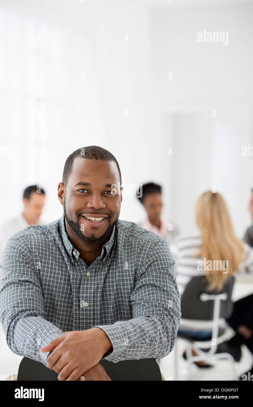 Office interior. A man seated separately from a group of people seated ...