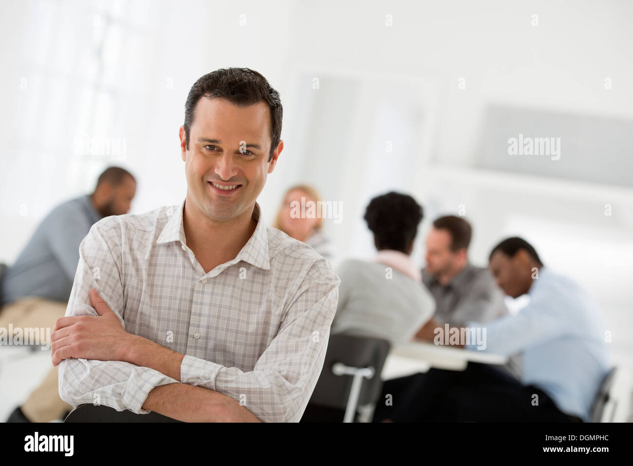 Office interior. A man seated separately from a group of people seated ...