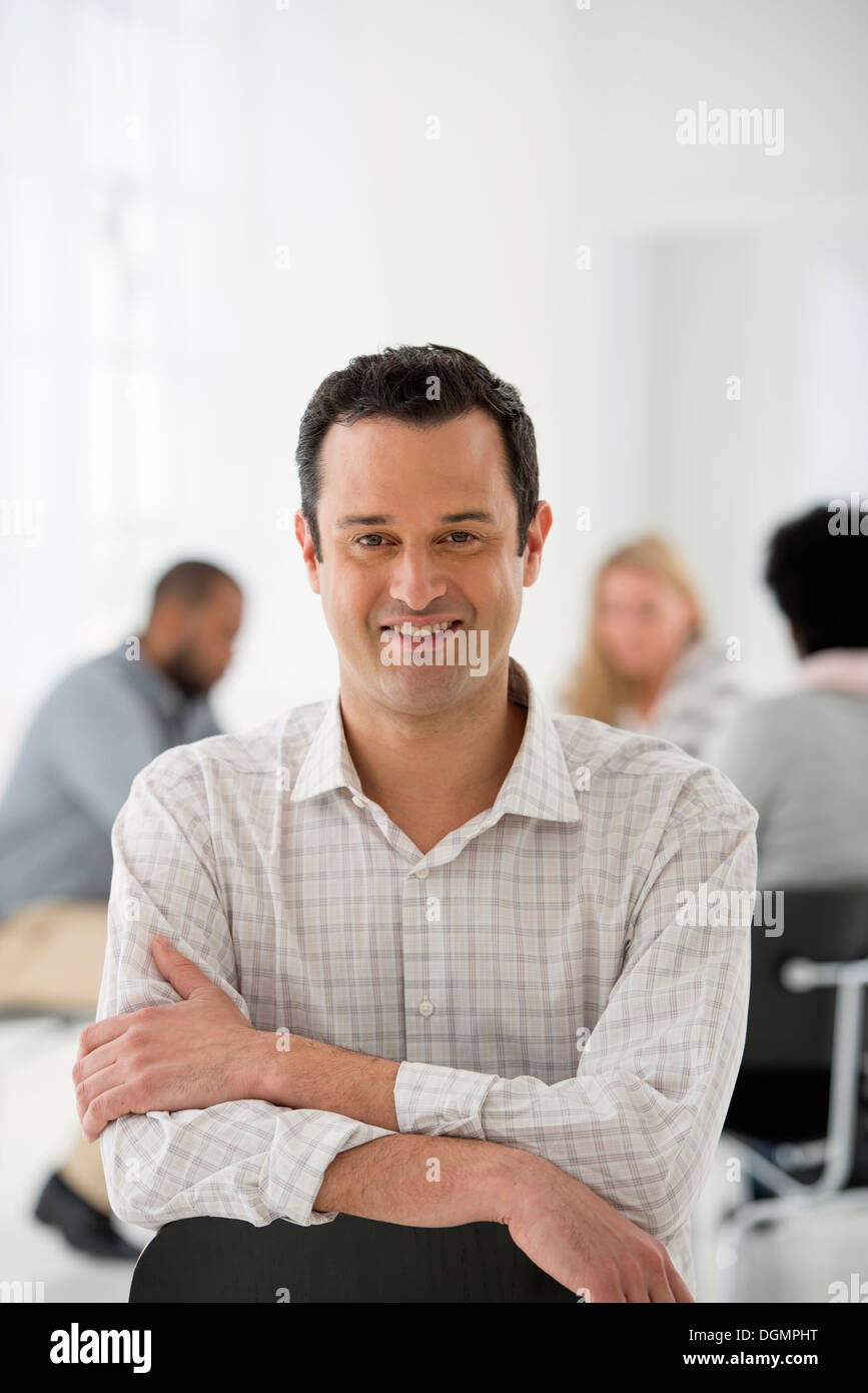 Office interior. A man seated separately from a group of people seated ...