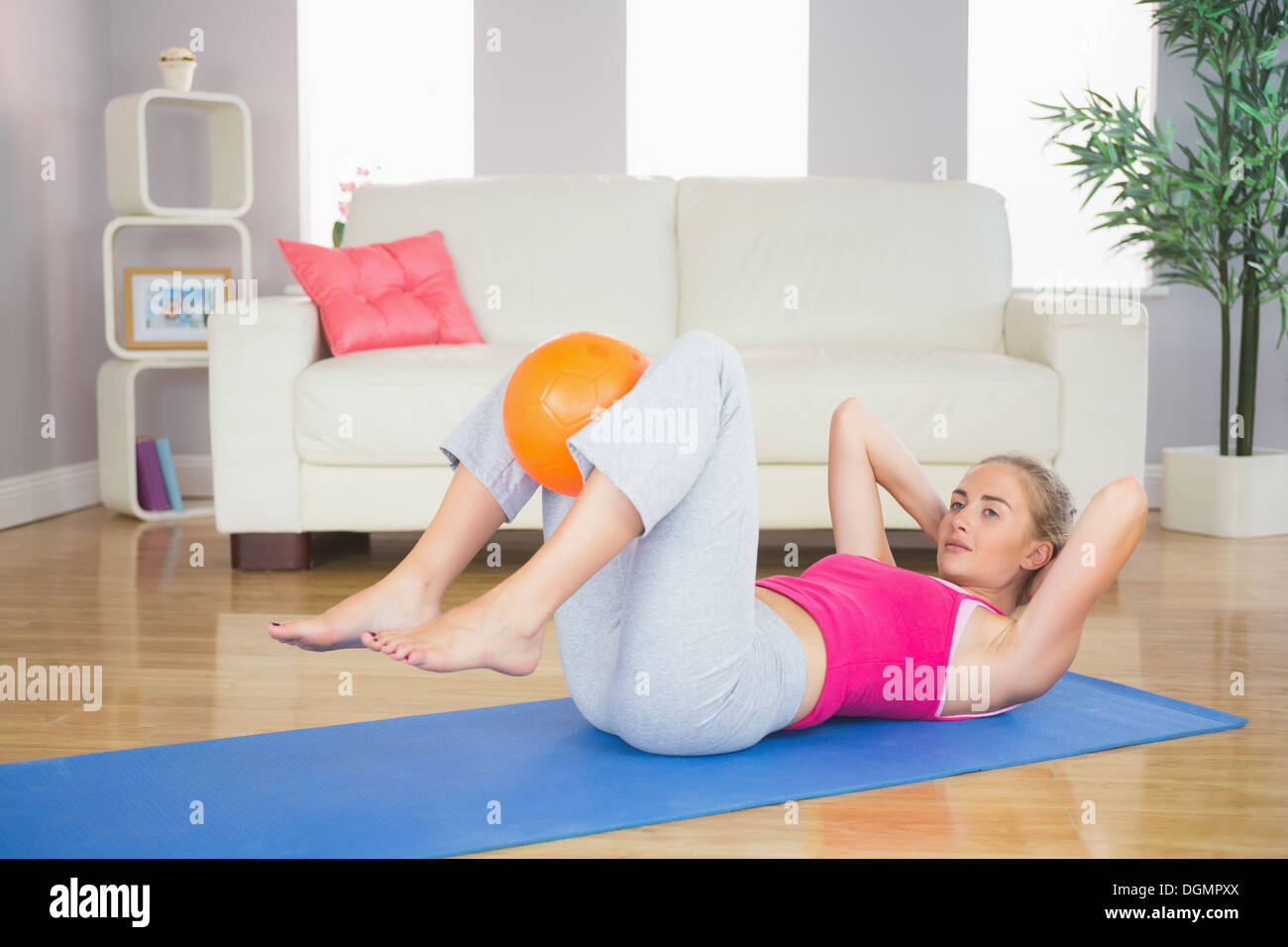 Sporty calm blonde doing sit ups holding ball between knees Stock Photo ...