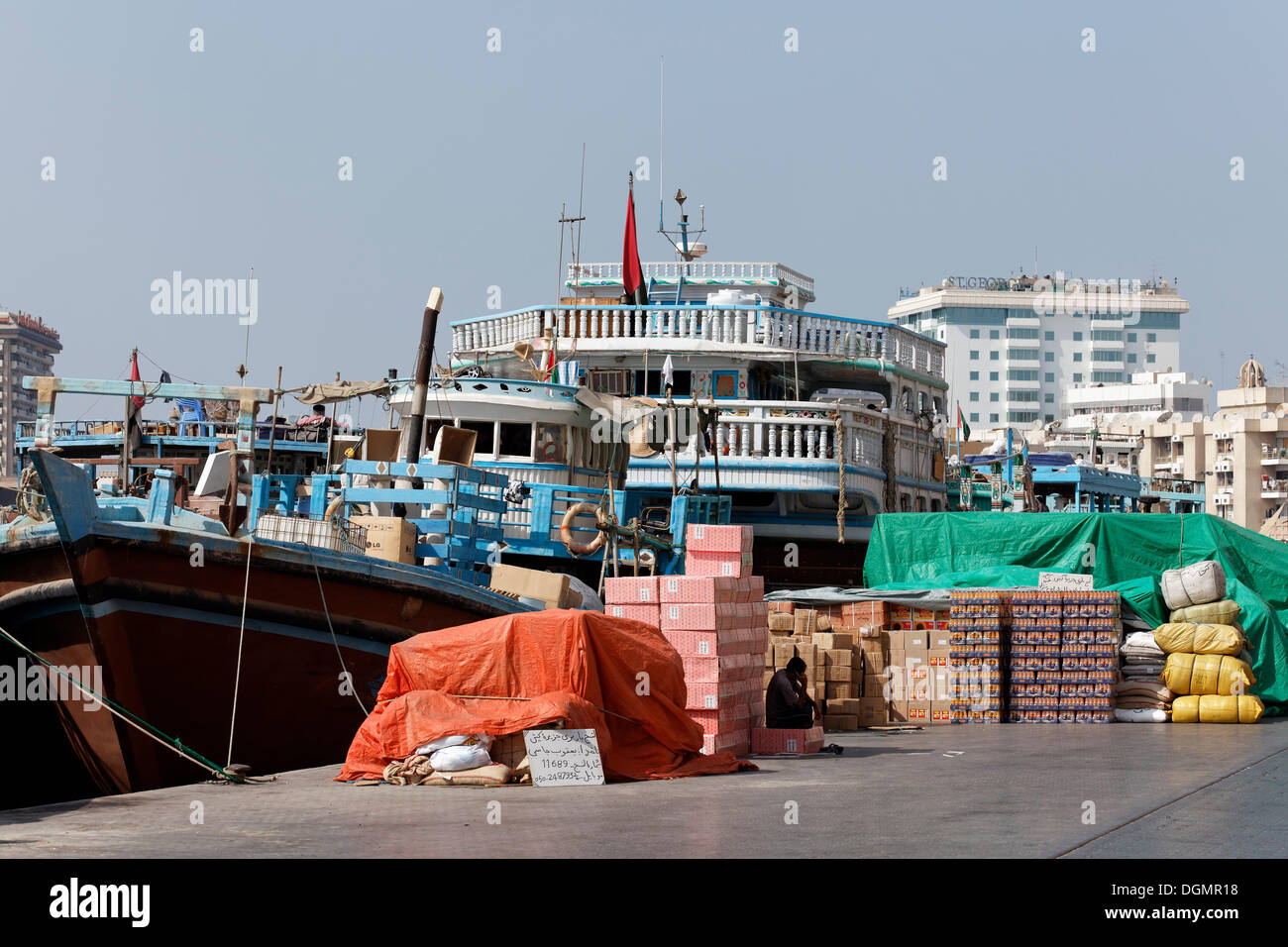 Cargo in front of an old wooden cargo ship, dhow or dau on Dubai Creek ...