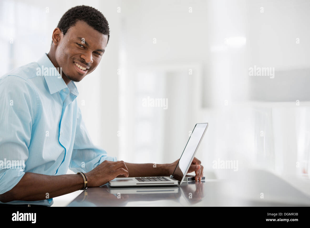 Office interior. A man seated at a table, using a laptop computer Stock ...