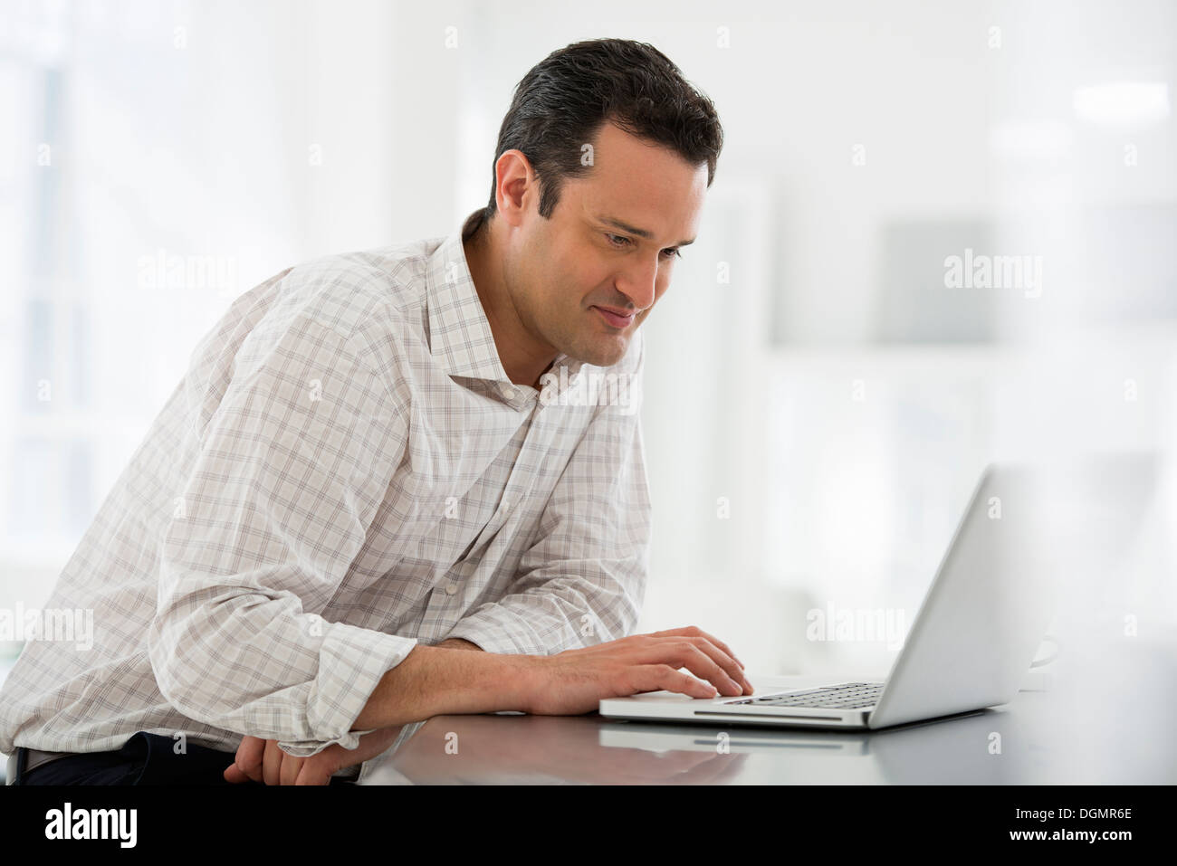 Office interior. A man seated at a table, using a laptop computer Stock ...