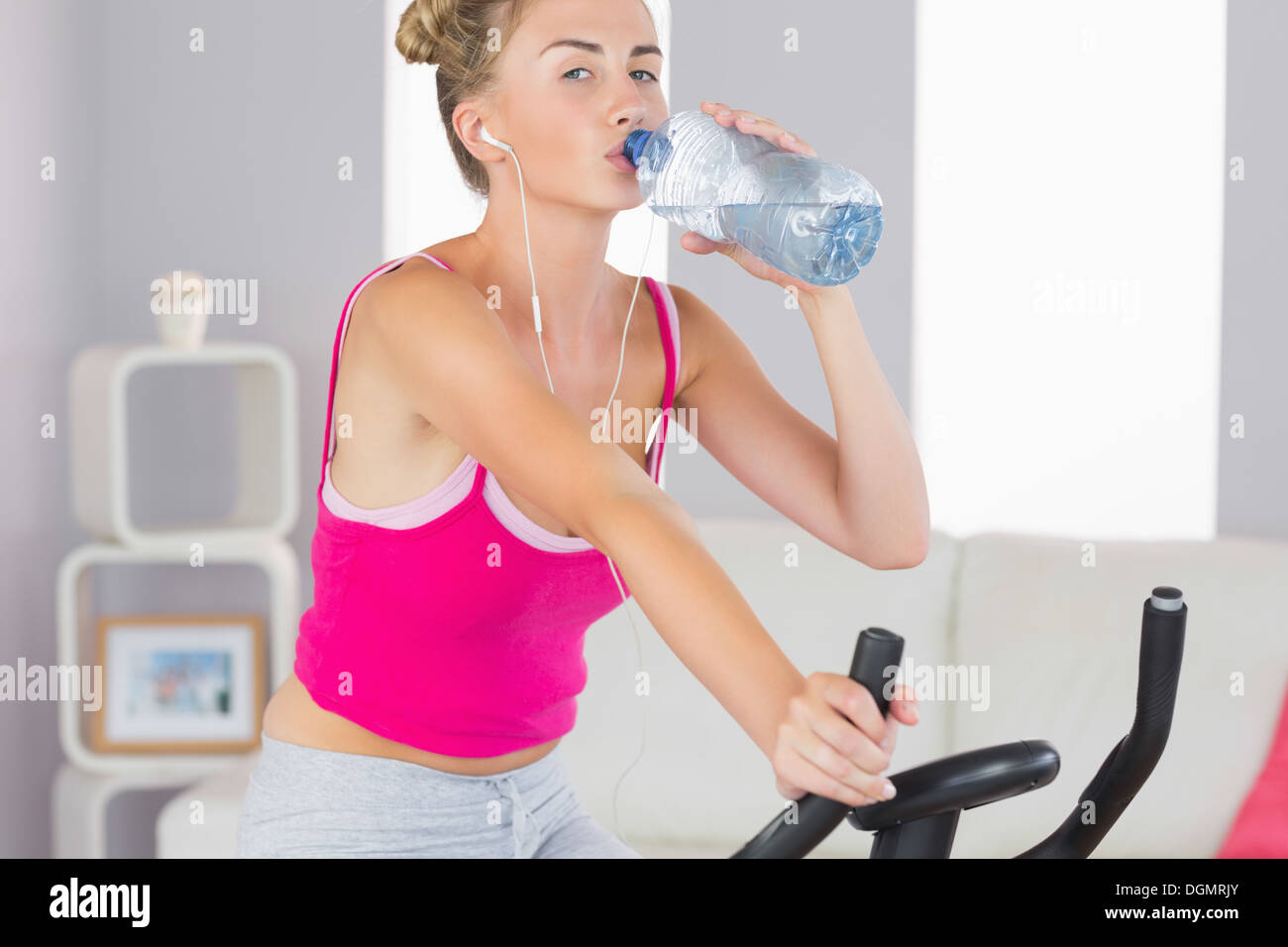 Sporty blonde training on exercise bike drinking water Stock Photo - Alamy