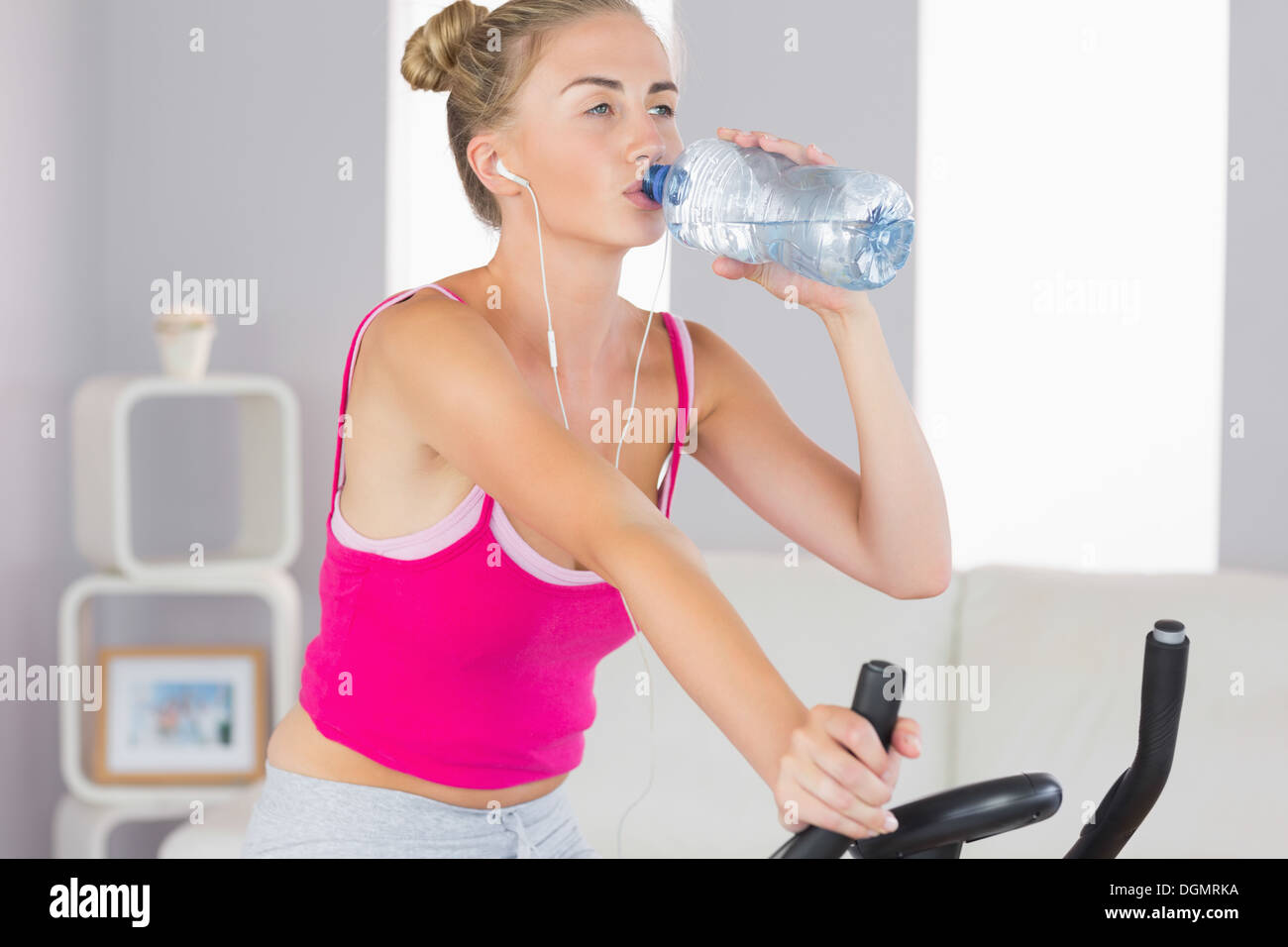 Sporty focused blonde training on exercise bike drinking water Stock ...