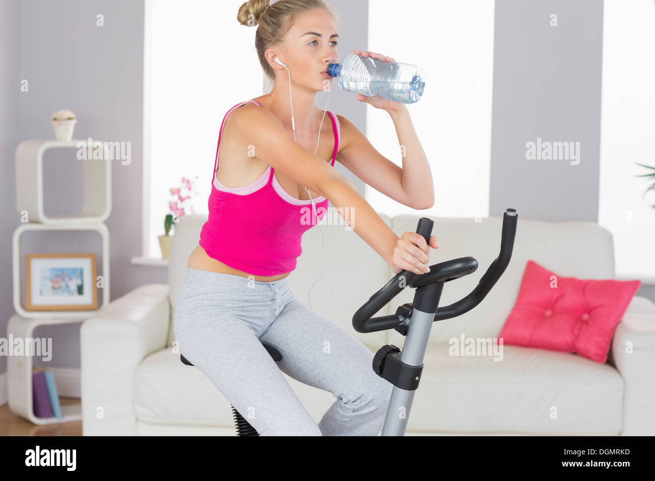 Sporty determined blonde training on exercise bike drinking water Stock ...