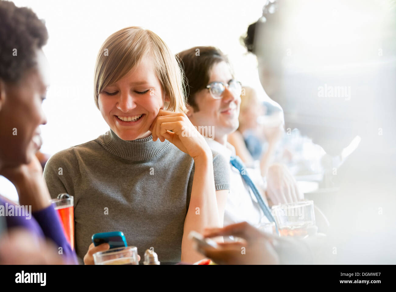 City life. A group of people in a café, checking their smart phones ...