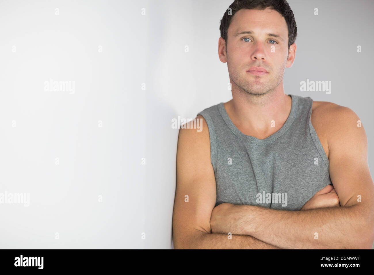 Sporty handsome man leaning against wall with arms crossed Stock Photo - Alamy