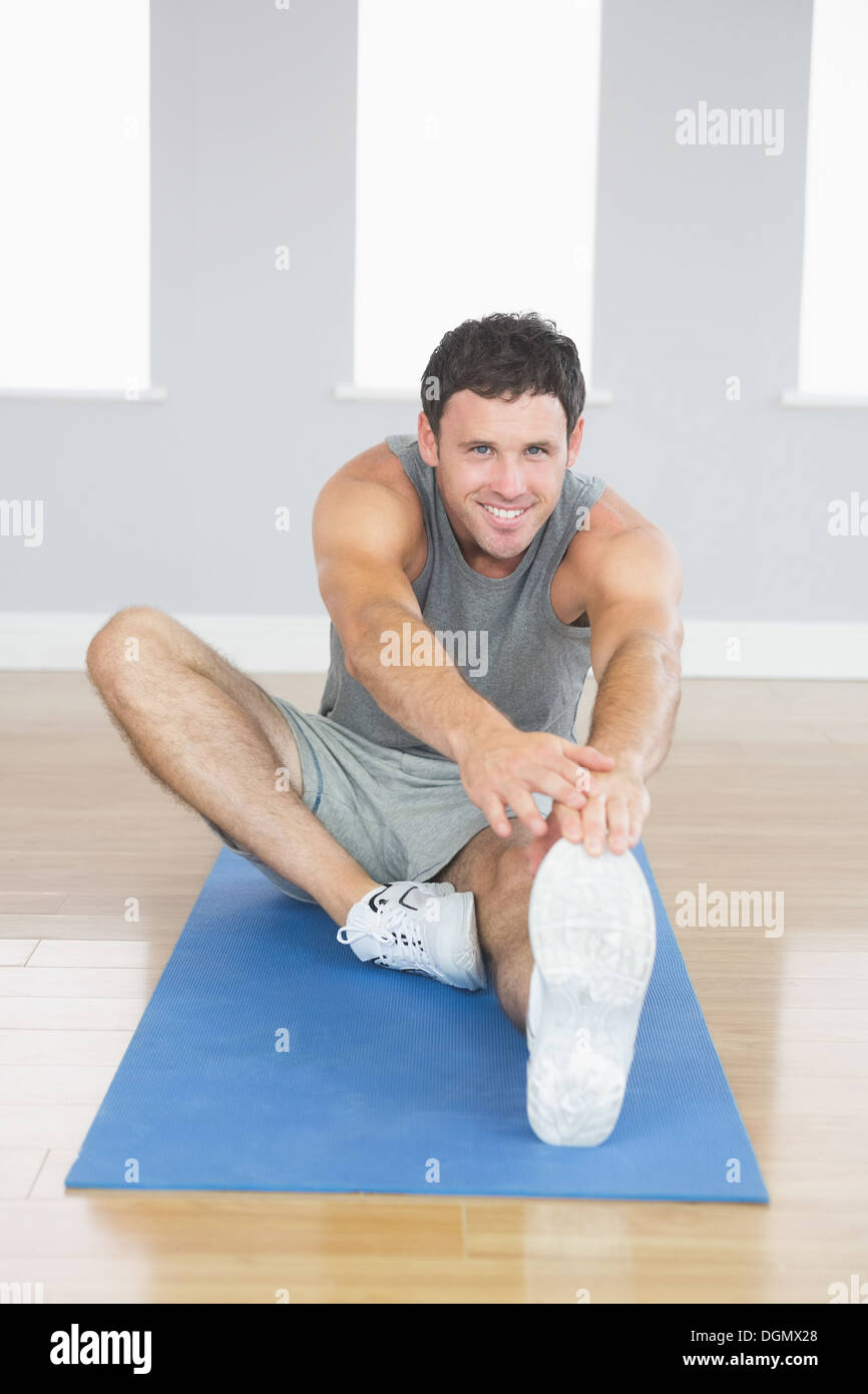 Smiling sporty man stretching his right leg Stock Photo - Alamy