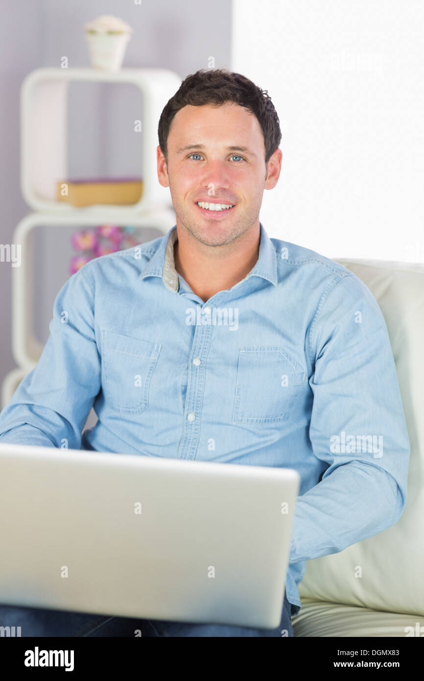 Happy casual man sitting on couch using laptop Stock Photo - Alamy