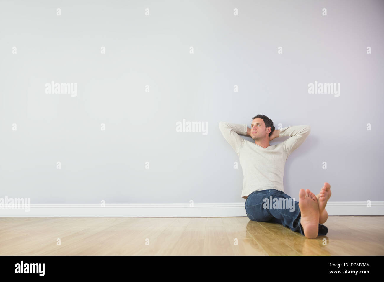 Casual pensive man leaning against wall with crossed arms Stock Photo ...