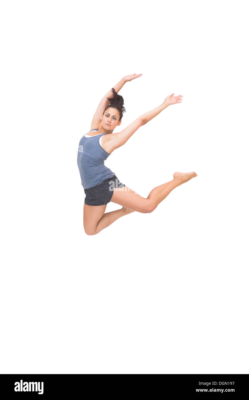 Pretty sporty brunette jumping in the air with arms up Stock Photo - Alamy