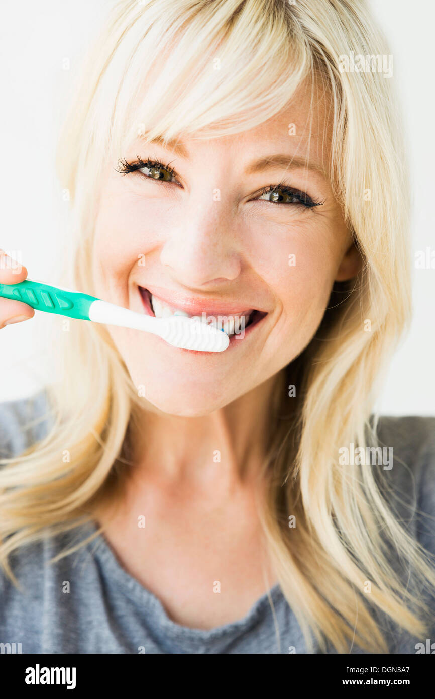 Studio portrait of blonde woman cleaning teeth Stock Photo - Alamy