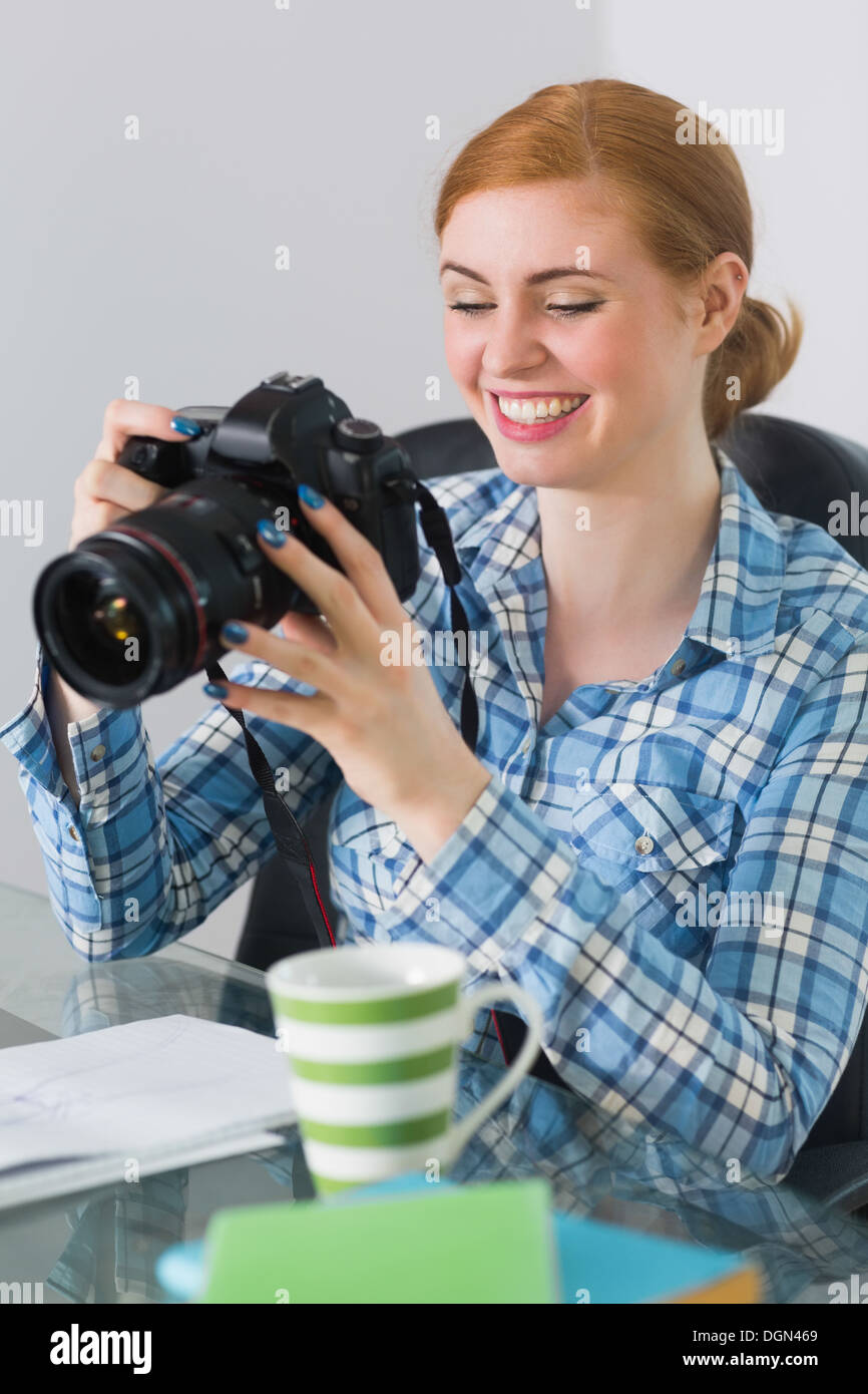 Happy photographer sitting at her desk looking at camera Stock Photo ...
