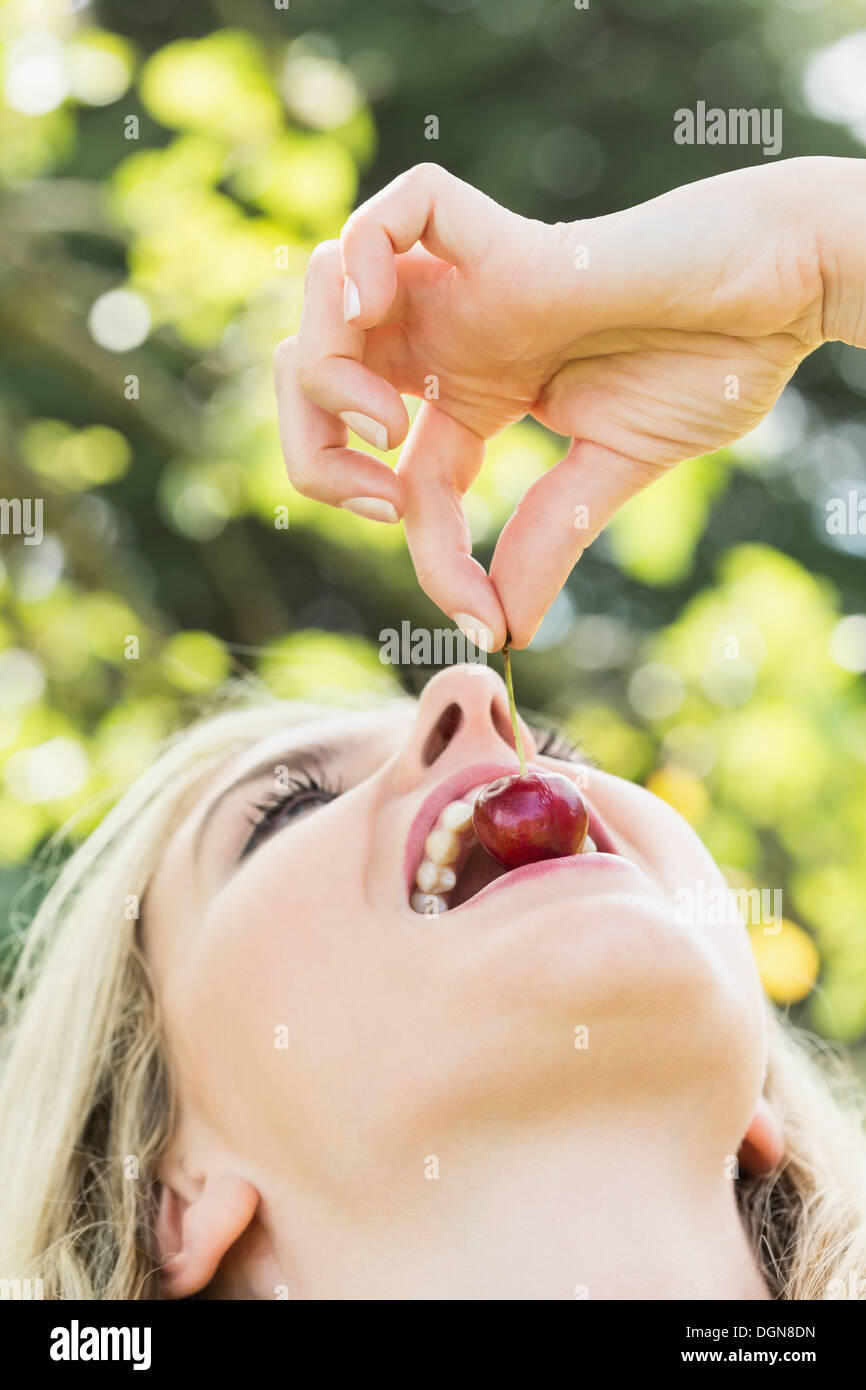 Blonde woman eating a cherry Stock Photo - Alamy
