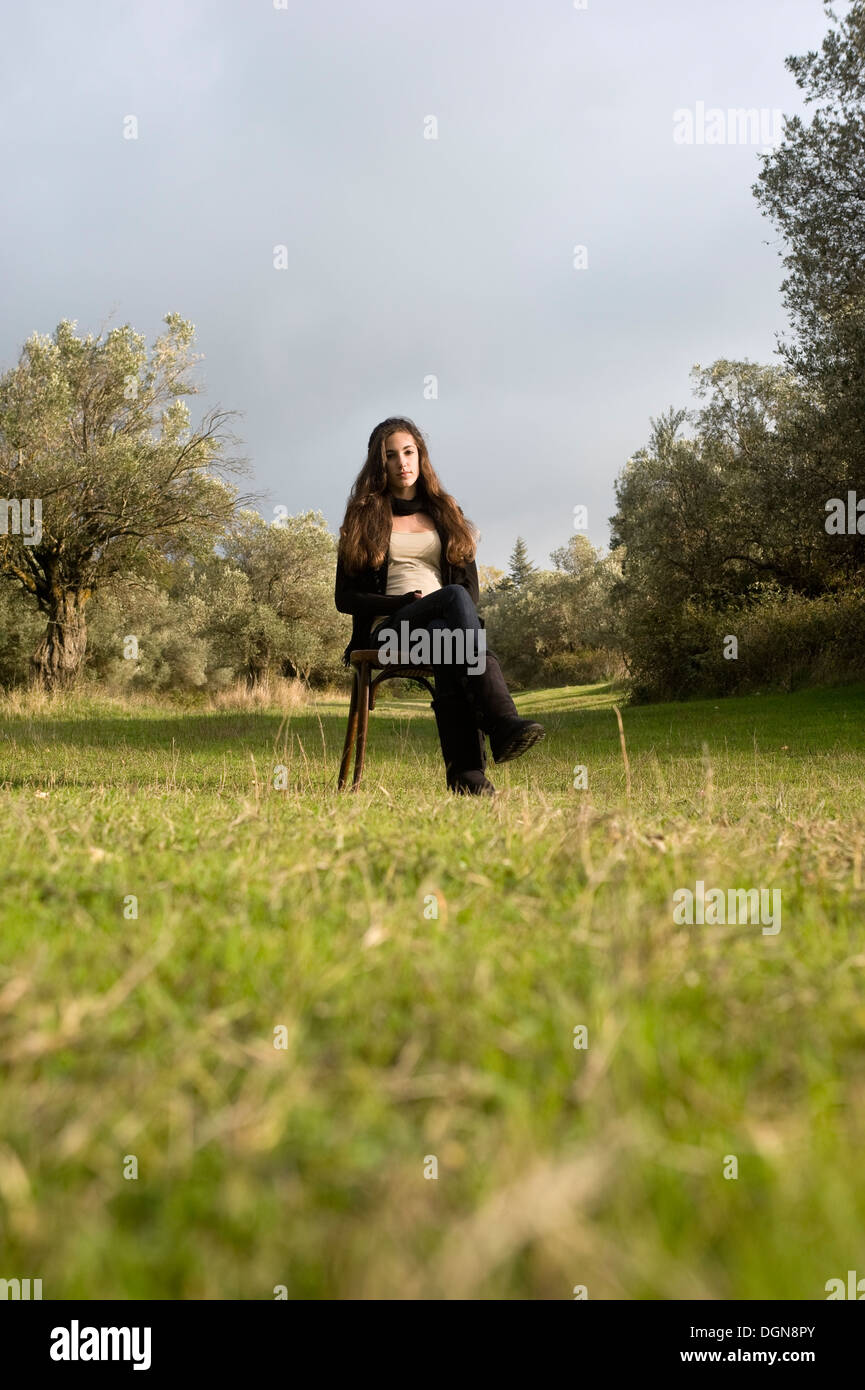 Teenage girl sitting on a chair in a field Stock Photo - Alamy