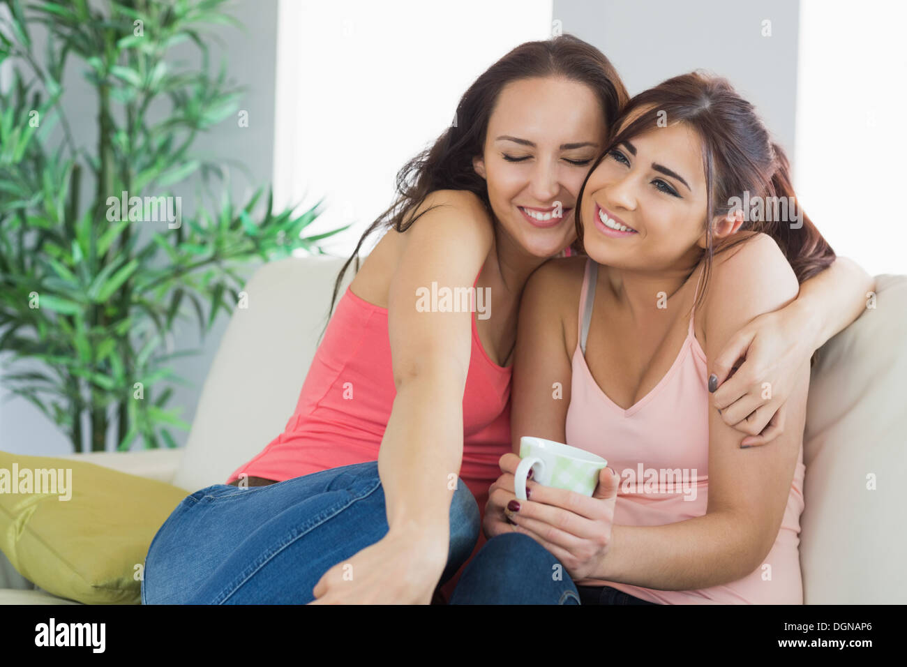 Two embracing women sitting on a couch Stock Photo - Alamy
