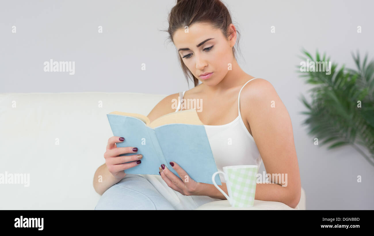 Concentrated young woman reading a book Stock Photo - Alamy