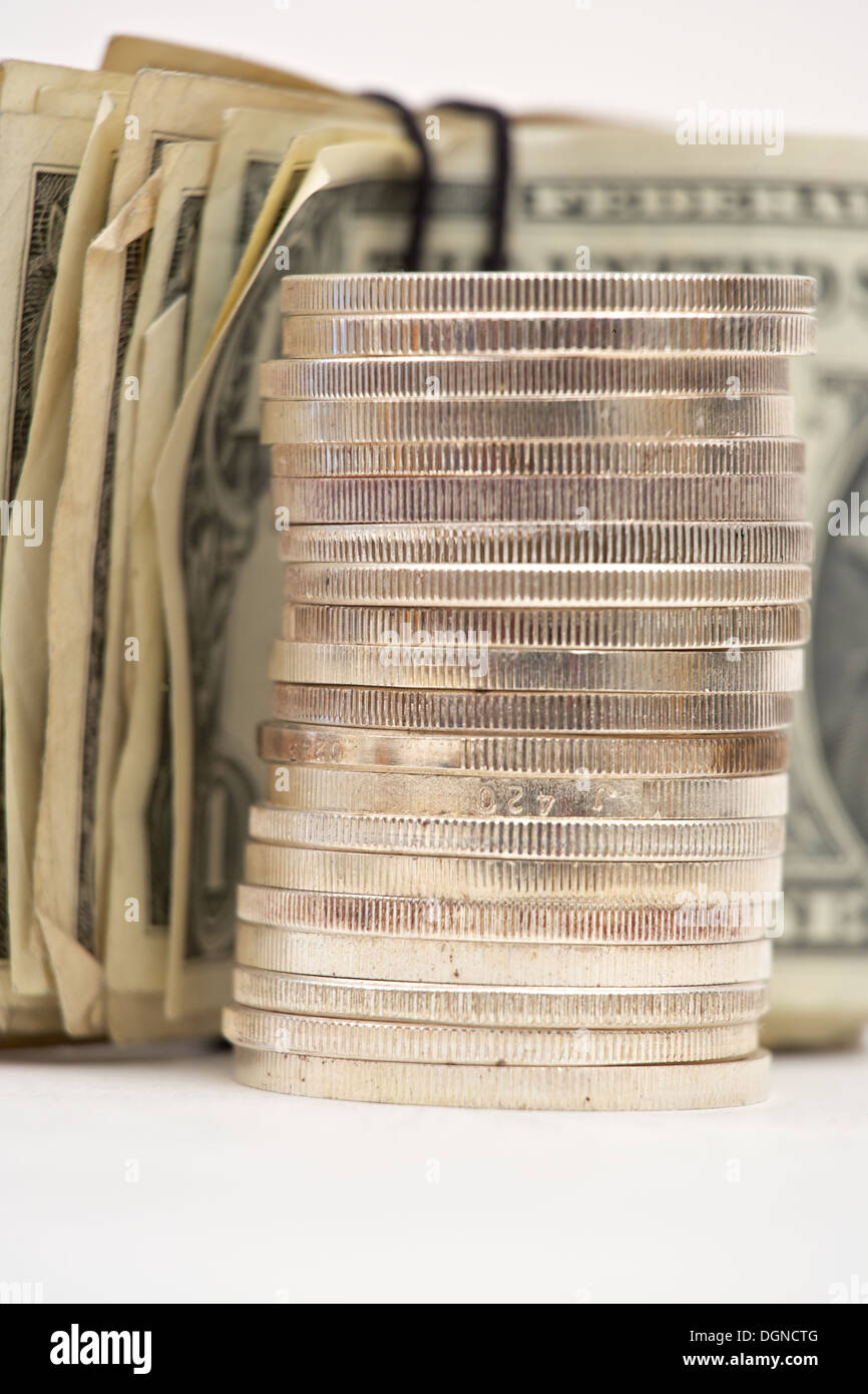 Stack of silver coins with a wad of money Stock Photo - Alamy