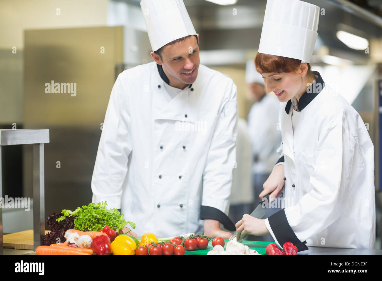 Female chef slicing vegetables with colleague Stock Photo - Alamy