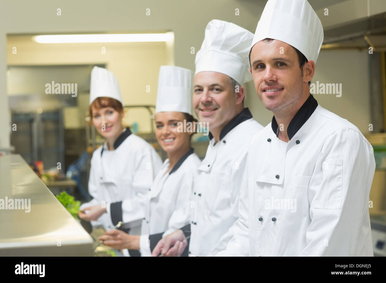 Four chefs working in a kitchen standing in a row Stock Photo - Alamy