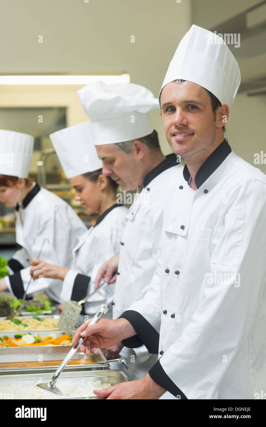 Happy chef standing at serving tray Stock Photo - Alamy