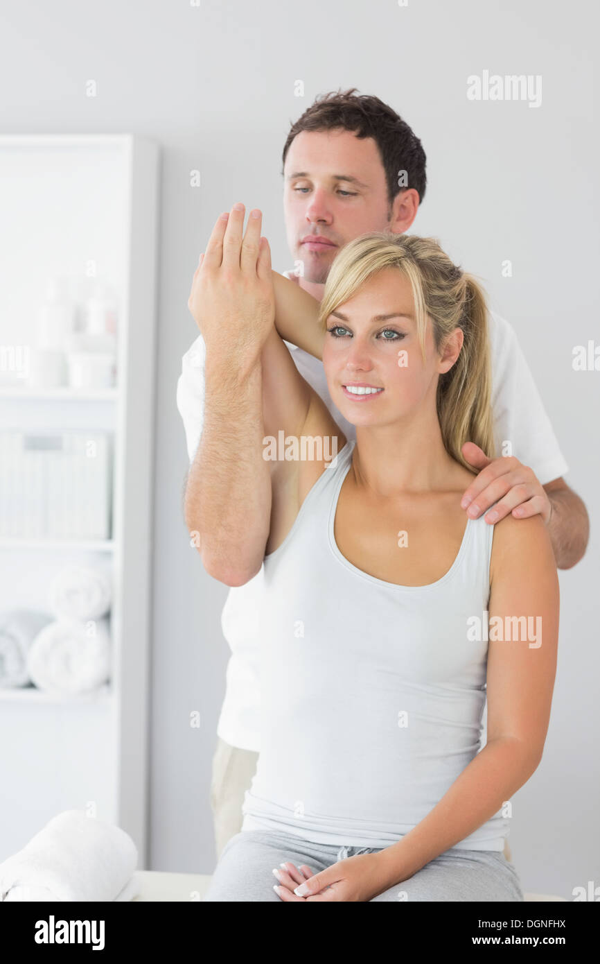 Attractive physiotherapist controlling patients arm Stock Photo - Alamy