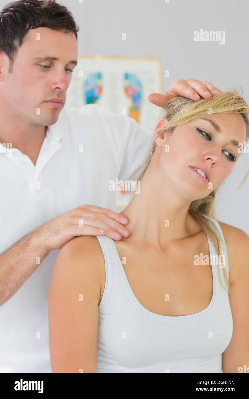 Good looking physiotherapist examining patients neck Stock Photo - Alamy