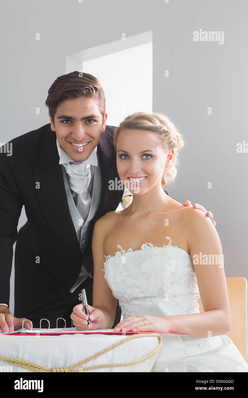 Young married couple sitting at table signing wedding register Stock ...